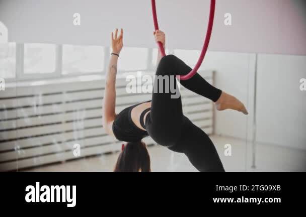 Young gymnastic woman showing acrobatic trick with a ring hanging up ...