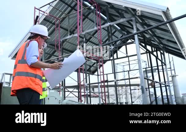 Young engineers working. Plan for construction of a warehouse. See the ...