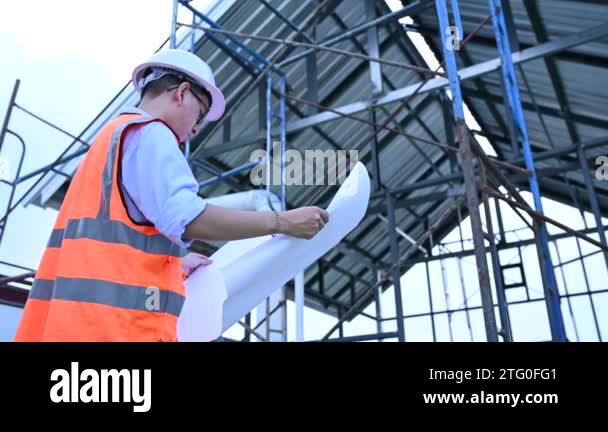 Young engineer working. Plan for construction of a warehouse. See the ...