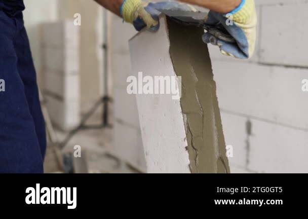 Bricklayer applies adhesive glue on autoclaved aerated concrete blocks ...