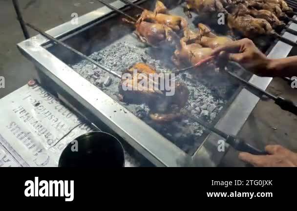 Chicken roasted on spit being grilled over the bright glowing beech ...