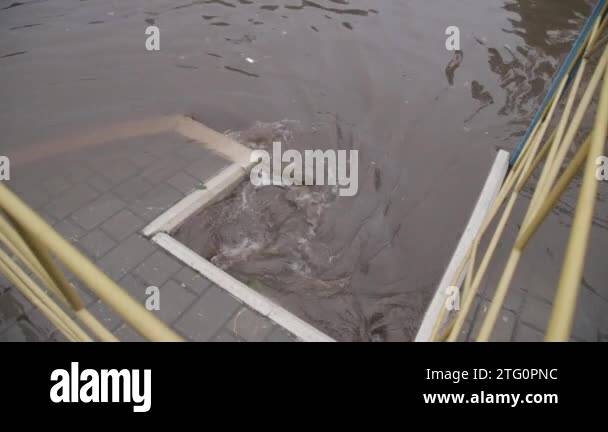huge puddle on city street. Water goes splashing down the drain. Road ...