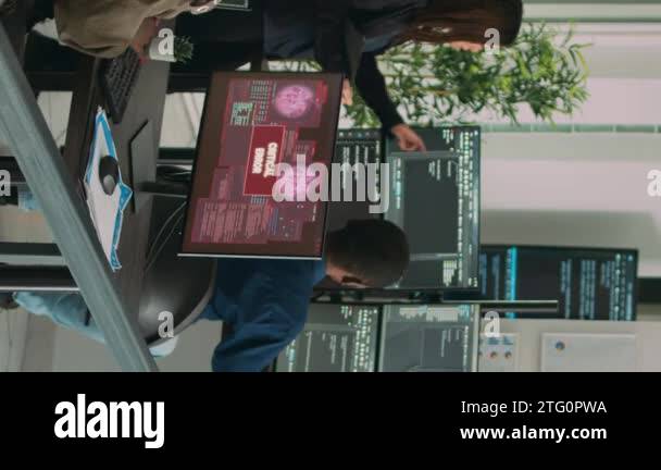 Vertical video: Diverse group of app developers working with hacked computer, dealing with ...