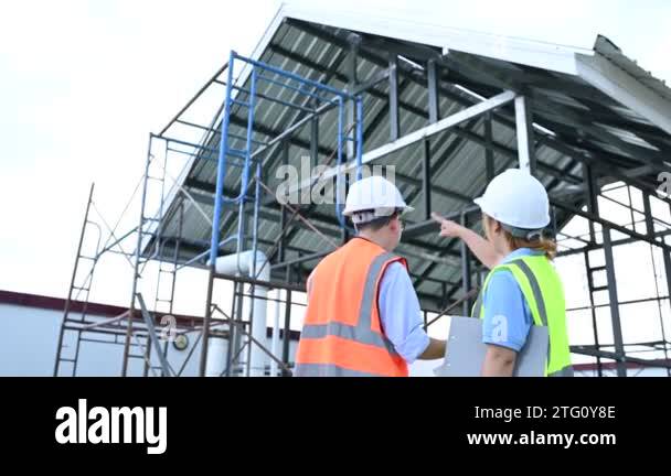 Young engineers working. Plan for construction of a warehouse. See the construction drawings for ...