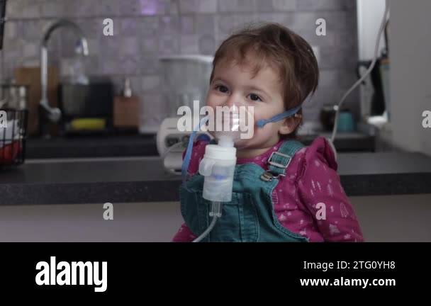 Cute little girl in the mask of an inhaler. Procedure of inhalation at ...