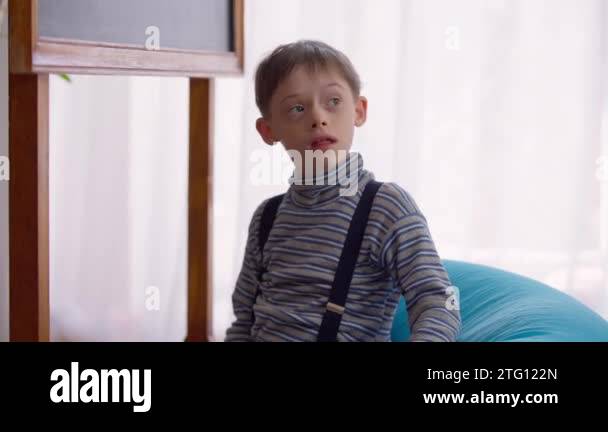 Curios autistic boy sitting on bag chair in classroom listening ...