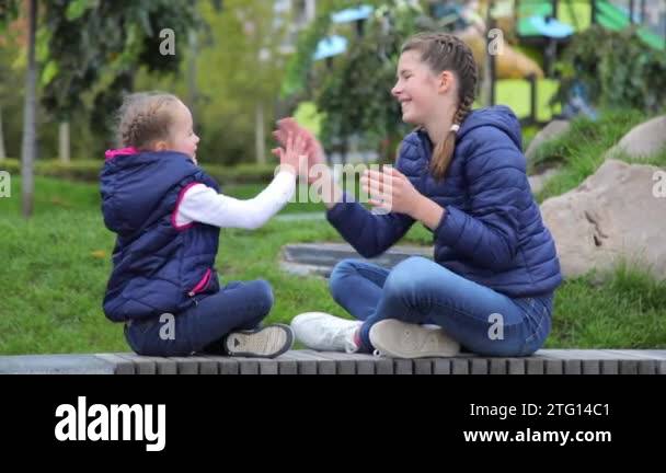 Two happy caucasian girls in casual clothes play clapping their hands ...