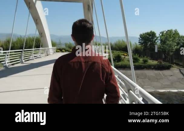 Young man walking across the bridge, front view of young man crossing ...