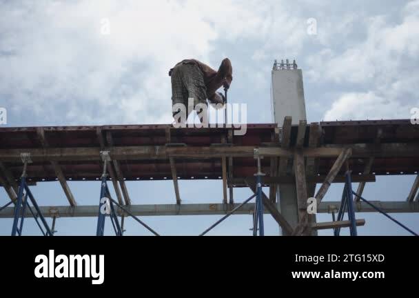 Man On Scaffold Platform, Bending Down Fabricating Rebar Against Sunny ...