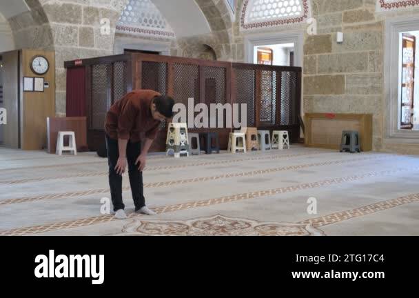 Muslim man praying in a mosque, bowing on his knees, performing ruku ...