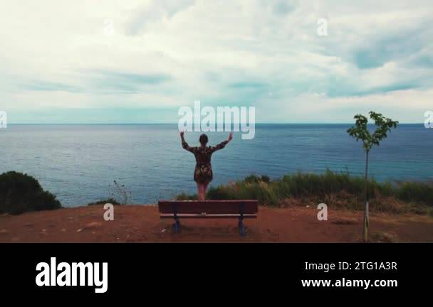 One single person standing high nearby the seashore with hands high in ...