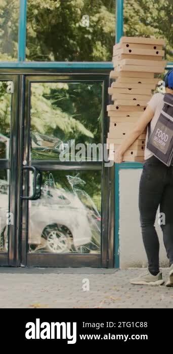 Vertical video: Fastfood delivery person dropping pizza boxes stack at ...