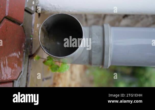 Close-up strong rain water flowing out from rain grey drain pipe on a ...