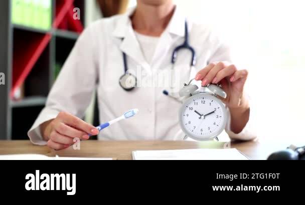 Dentist is working in dental hospital holding an alarm clock and ...