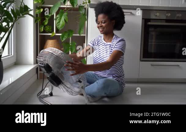 Curly-haired African American woman is sits on floor own house pointing ...