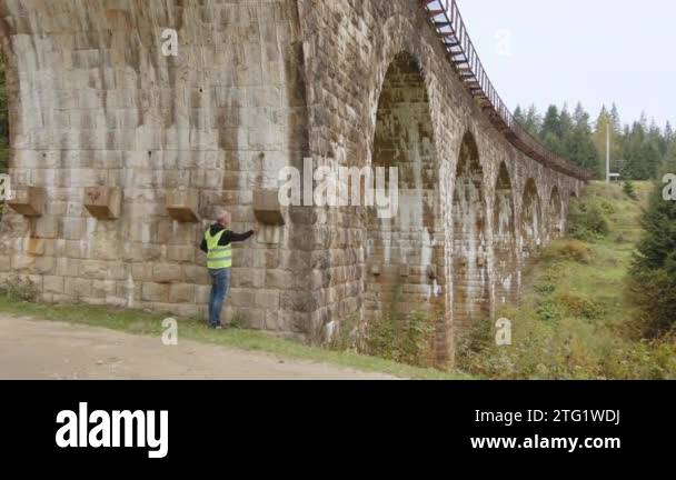 Inspection of bridges. A senior gray-haired engineer stands under a ...