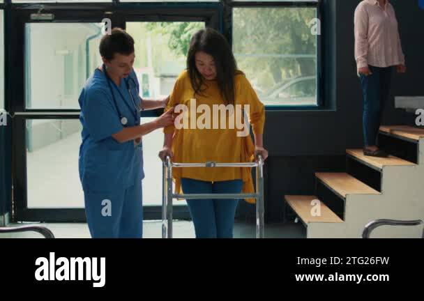Asian patient using walking frame to walk in medical clinic, doing ...