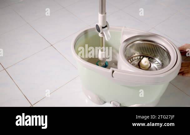 Woman holding mop with microfiber head spinning water in the bucket ...