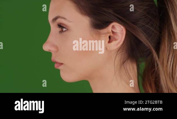Close-up profile of beautiful model posing in front green screen wall ...