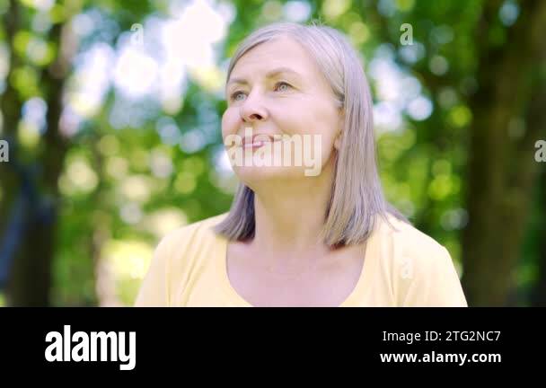 Close up portrait senior retiree woman standing in nature between ...