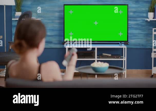 Static tripod shot of young woman switching channels while looking at ...