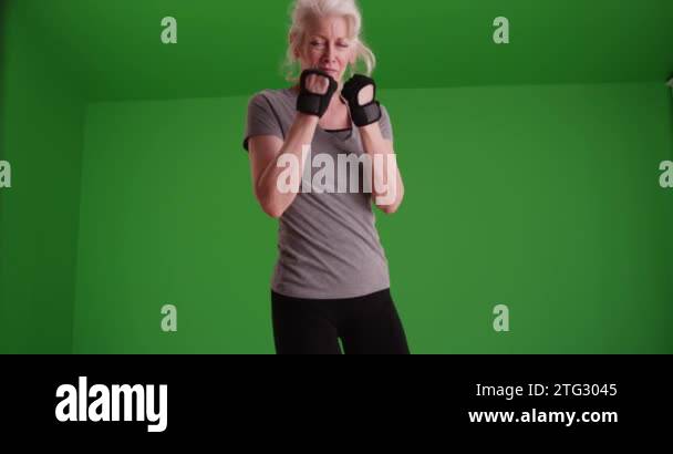 Energetic mature woman shadowboxing on greenscreen. Slow motion shot of ...