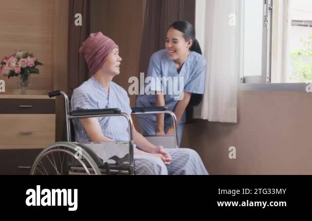 Uniformed young Asian female therapy doctor encouraging wheelchair male ...