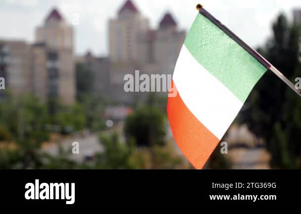 National Flag of Italy set against blue sky and city street. Italian ...