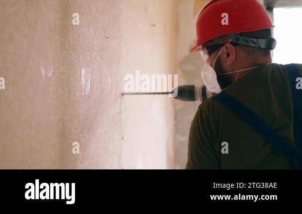Builder working with a rotary hammer drill. Contractor drills holes in ...