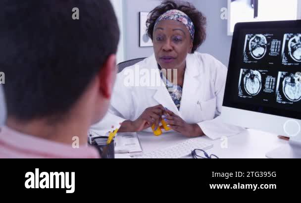Senior African doctor prescribing medication to young male patient with ...