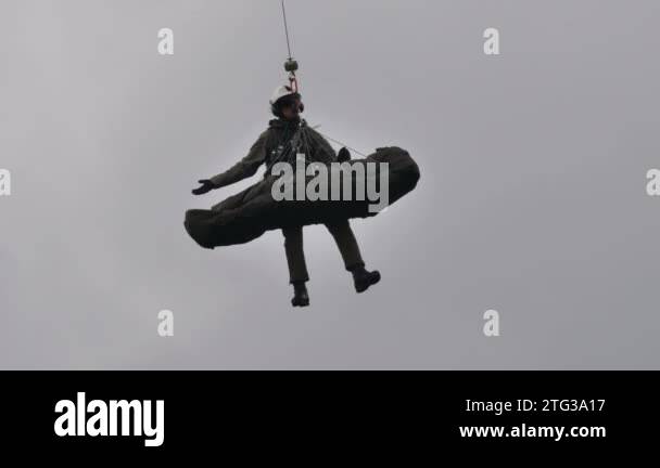 Helper with injured person on stretcher is hoisted with winch on ...