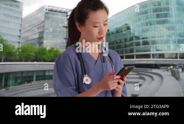 Serious millennial doctor reading text messages with smartphone outside ...