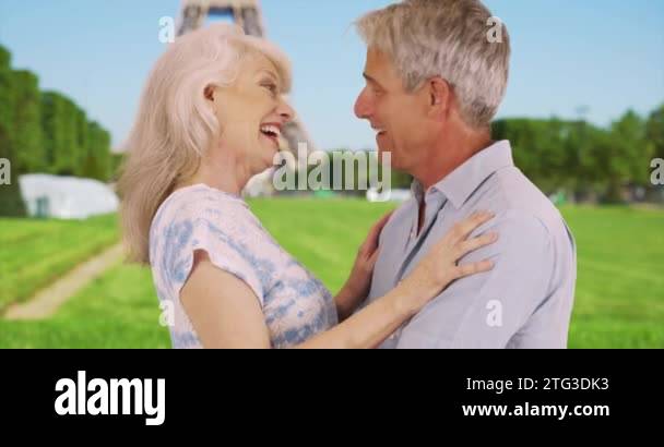 Mature couple hug near the Eiffel Tower. Happy retired male and female ...