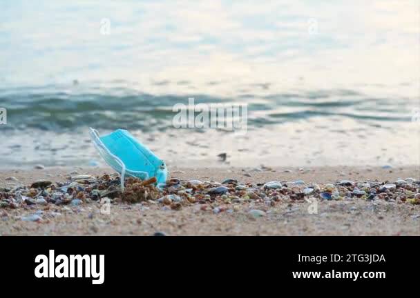 Used masks are discarded on sand on beach ,concept hazardous waste risk ...