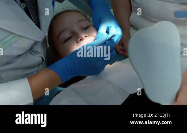 Woman dentist examines baby teeth of child little girl patient in ...