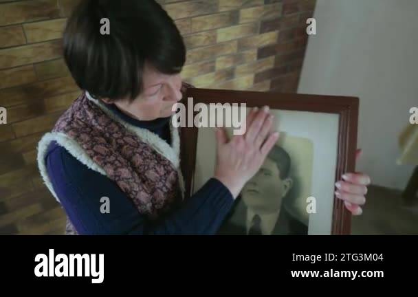Senior 60s woman wipe old photo portrait of an ancestor. Adult female ...