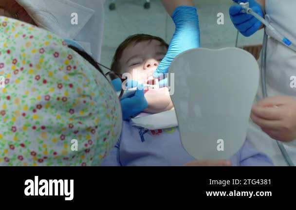 Woman dentist examines baby teeth of child little boy patient in clinic ...