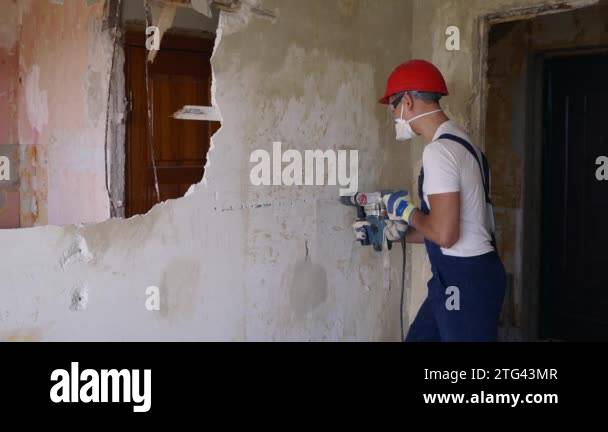 Builder working with a rotary hammer drill. Contractor drills holes in ...