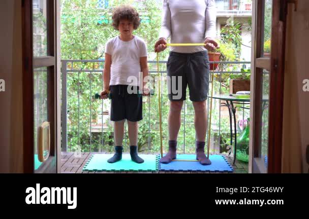 father and 7-year-old son boy do gym gymnastics at home on the balcony ...