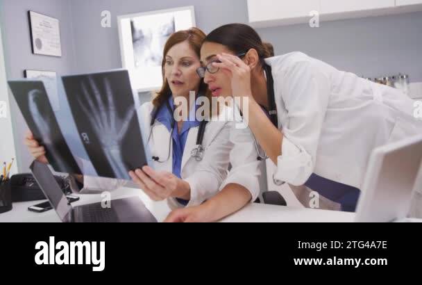 Portrait of lovely female doctor reviewing patients x rays of hand and wrist with senior ...