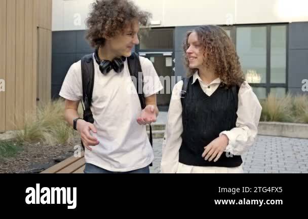 Two cute high school students, a guy and a girl, are walking around the ...