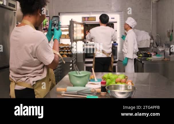 Young Asian male cooking class student brings tray of baked pies from ...