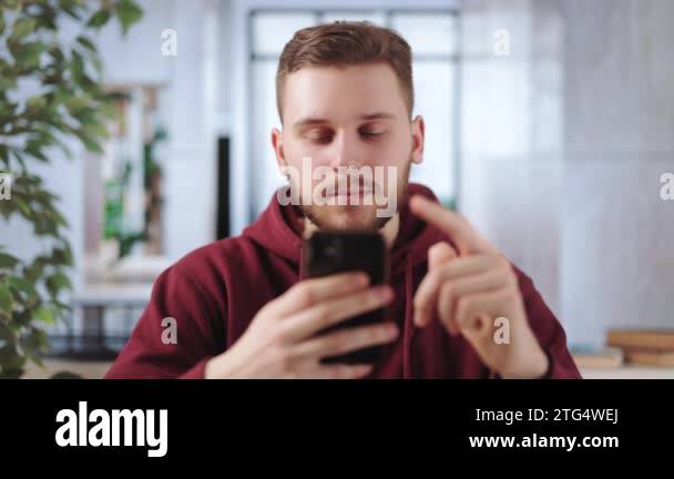 Positive young man scrolling news feed while resting from remote work ...