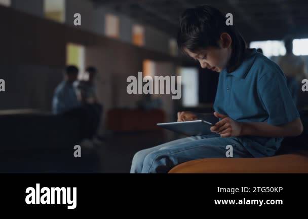 Focused boy using pad lose in online game sitting school hallway close ...