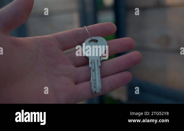 Hand of woman holds keys walking in yard to luxury triangle-shaped ...