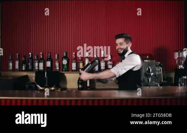 Positive young man in stylish formal wear shaking steel shaker behind ...