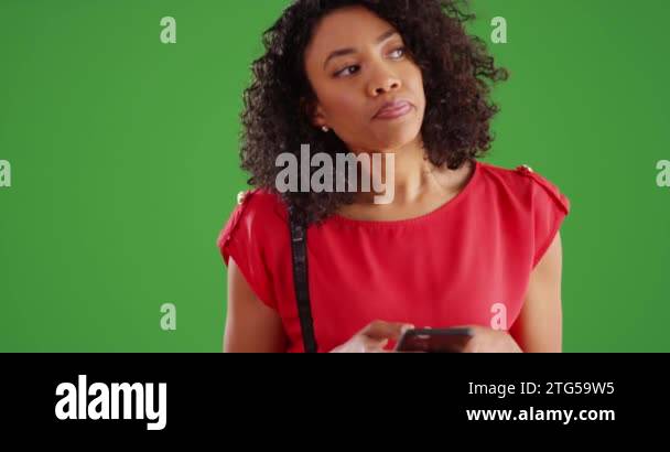 Pretty Black woman texting with cell phone and smiling on greenscreen ...