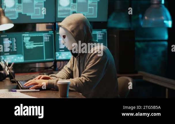 Cyber terrorist with mask hacking database servers, hacker with hood on hacking computer system ...