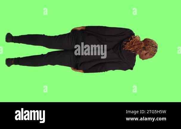 Vertical video: Young adult waiting in line on full body greenscreen ...