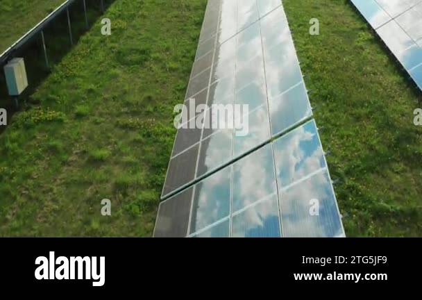Cloudy sky reflected on surface of modern sun panels installed on green ...